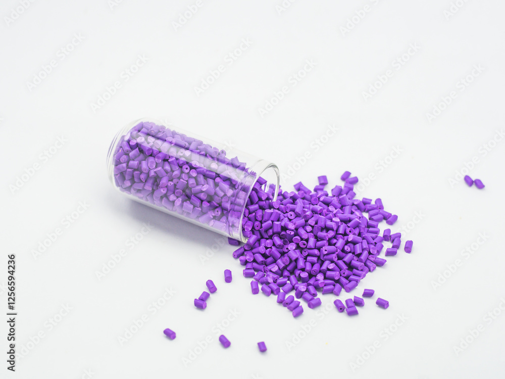 Purple masterbatch granules spilling from glass tube on white ...