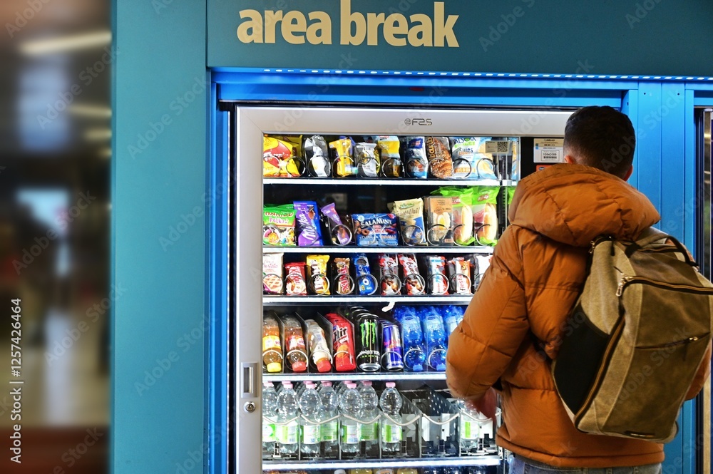 Male backview standing in front of food and drink vending machine at ...