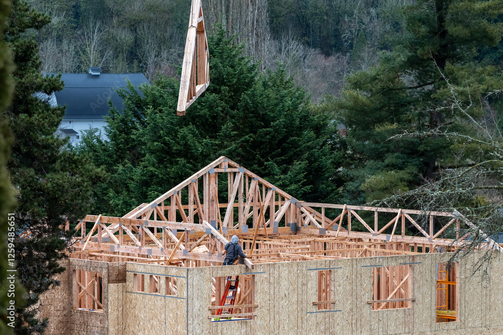 Workman on a ladder on second floor of new home under construction ...