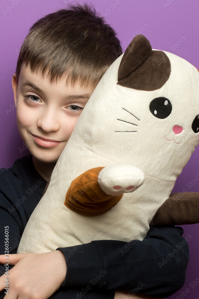 Smiling little boy cuddling a stuffed cat toy, symbolizing childhood ...