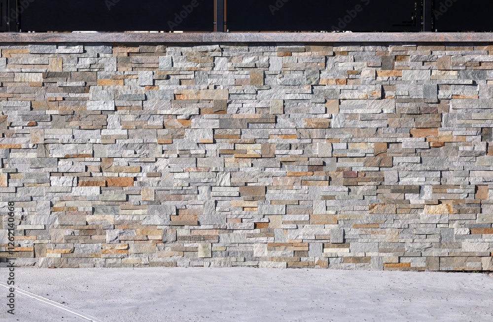 Fence made of faux stone veneer wall and black metal paneling on top ...