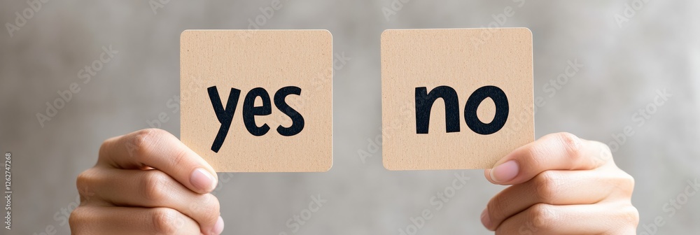 Hands holding two cardboard squares with the words yes and no written ...