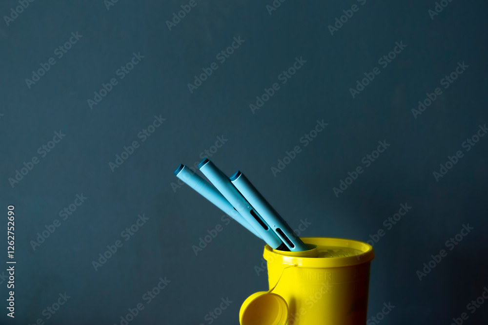 Couple of medicine syringe pen sticking out of toxic waste collection ...