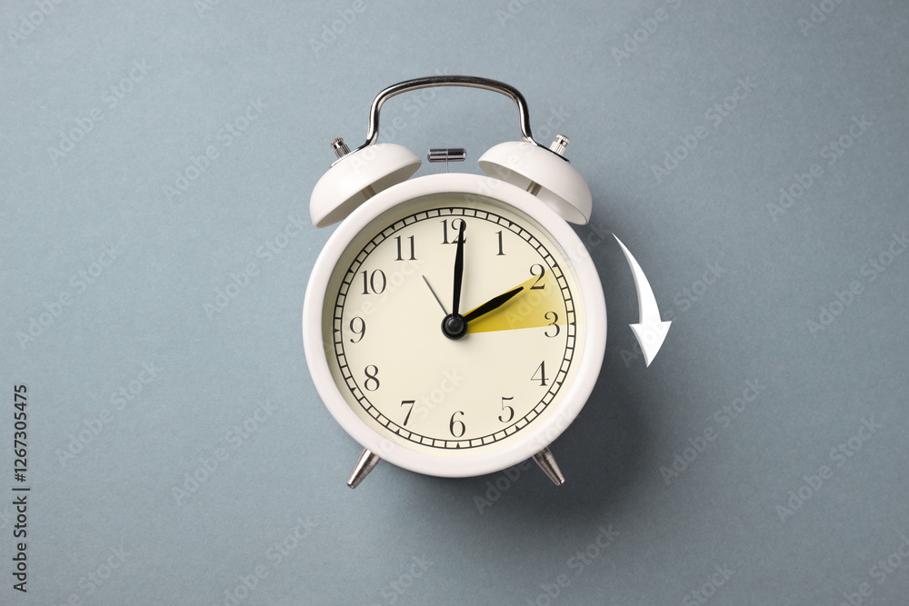 Daylight saving time. White alarm clock on grey background, top view ...