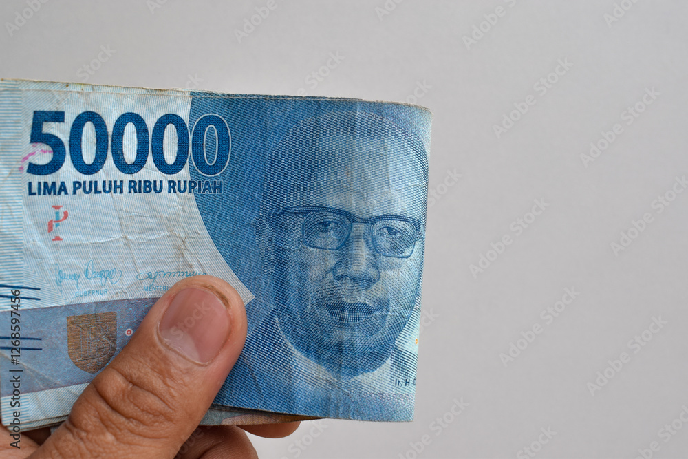 Indonesian rupiah currency. man's hand holding some fifty thousand ...