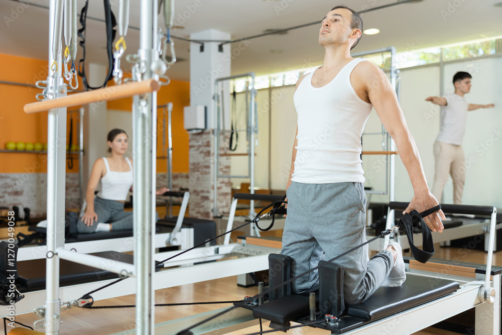 Man in gym with help of rope reformer performs exercises to strengthen ...