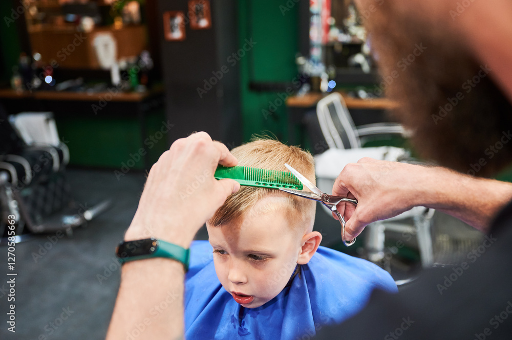 Behind shoulder view of hairdresser cutting little boy's hair. Cute boy ...