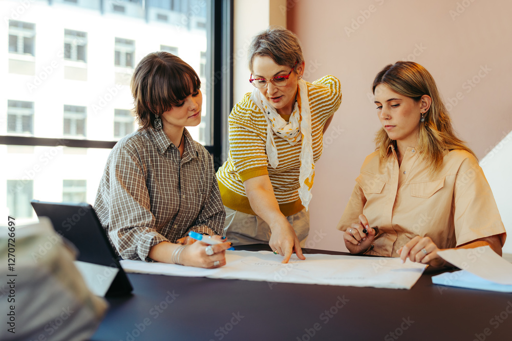 Professor guiding college students during a task in a modern classroom ...