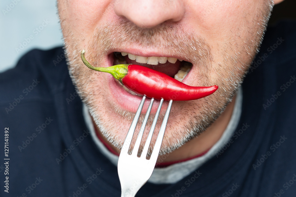 Expressive and funny man holding whole red chili pepper in his mouth ...