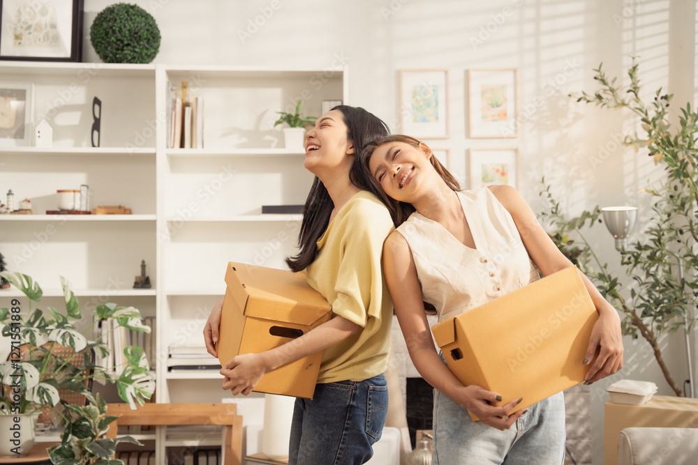 Happy Asian girl friends holding cardboard boxes moving to the new home ...
