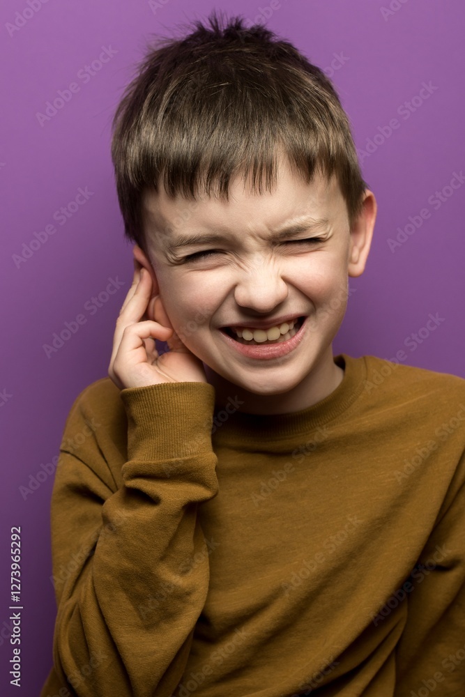 Child holding ear, wincing in pain, purple background. Ideal for themes ...