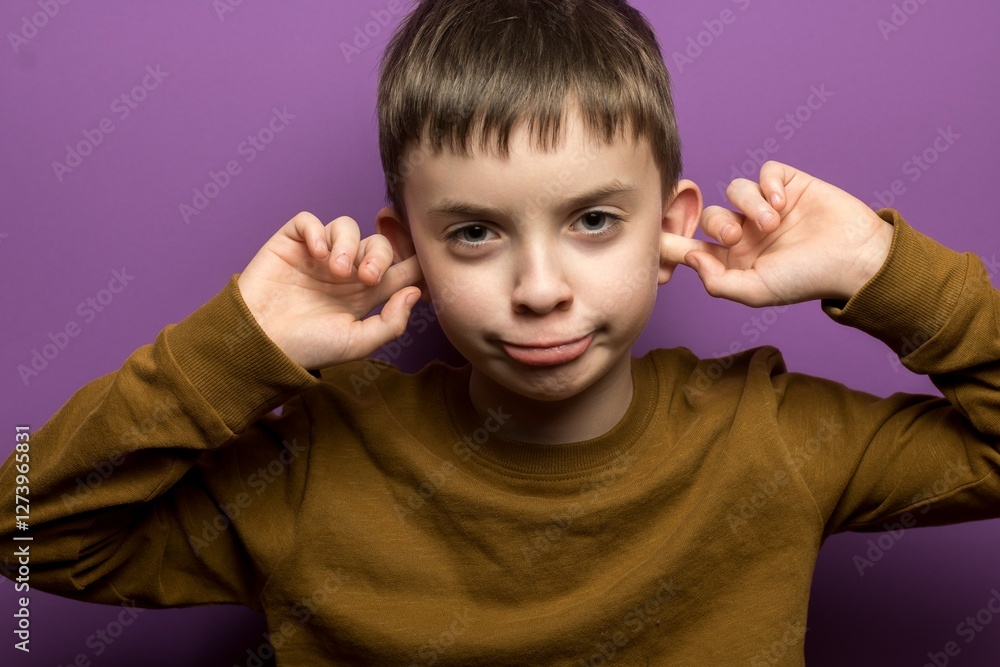 Child covering ears with hands, playful expression, purple background ...