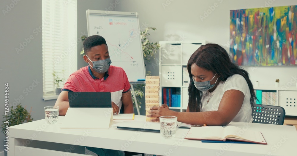 Break in the office from work, two young interns are building tower of ...