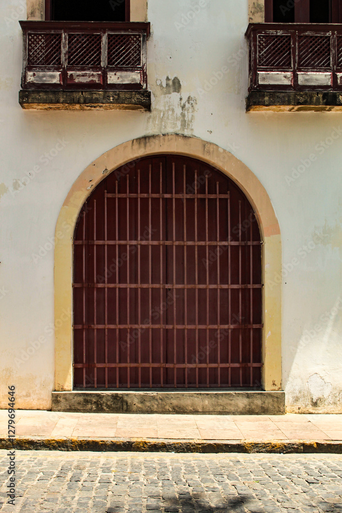 Roman arch, with an old wooden gate and iron railing, in a colonial ...