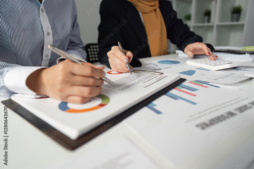 Financial analysts reviewing tax documents and data visualization in a ...