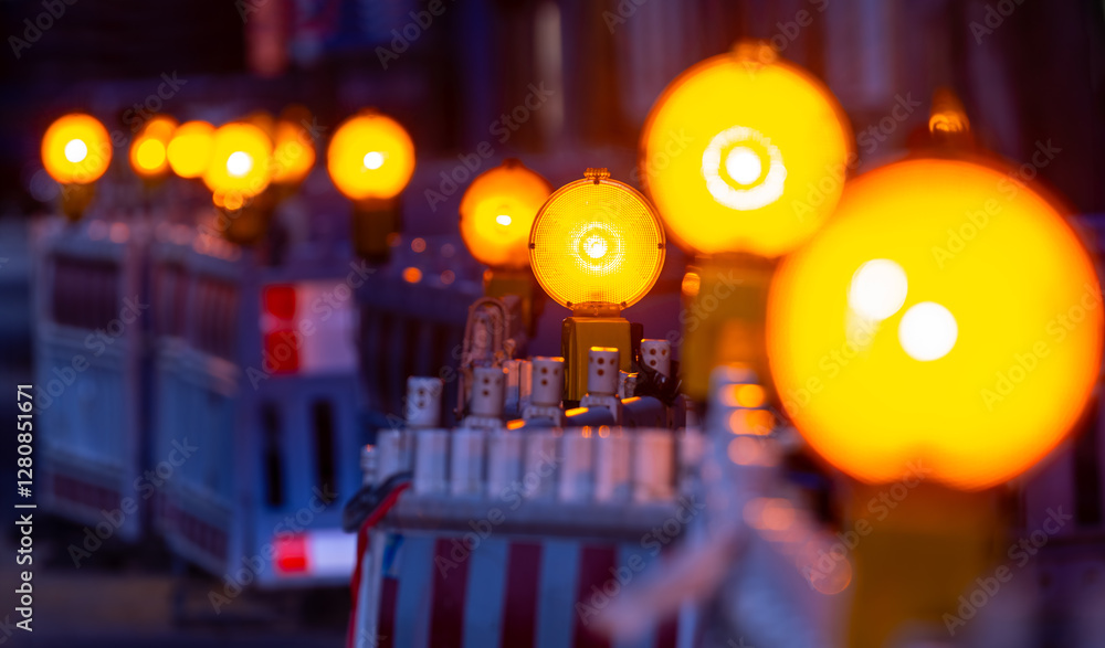 Bright yellow-orange flashing lights at a roadworks site in Germany at ...