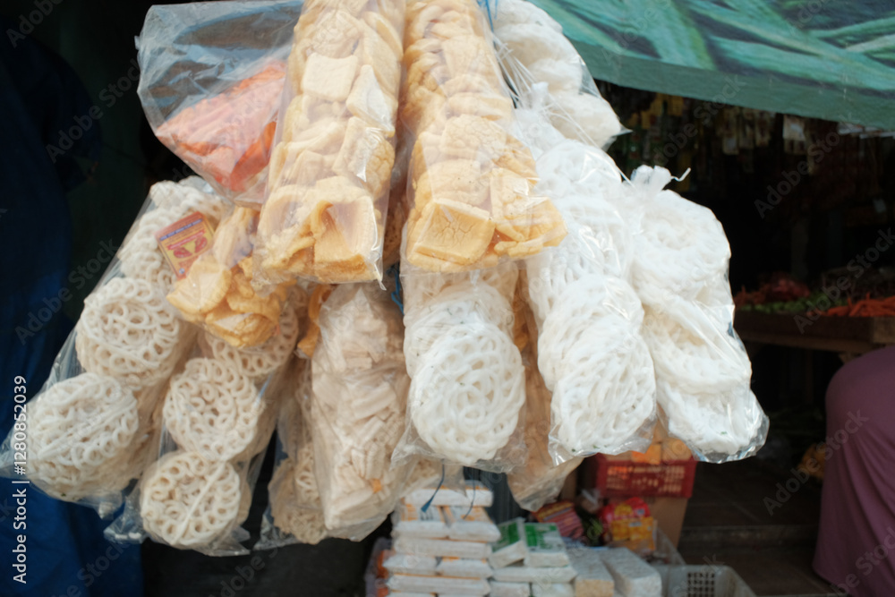 Various types of crackers (kerupuk) hanging in clear plastic packaging ...