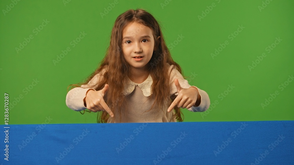 Little girl child peeks out and pointing down at blue space, positive expression, isolated on ...
