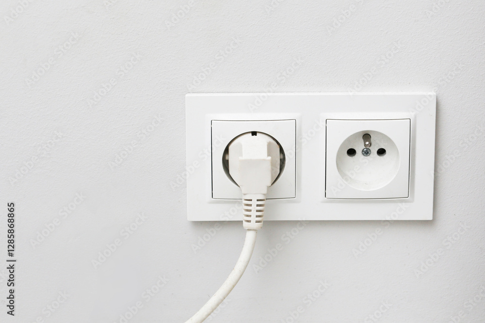 Electrical socket isolated on gray wall. White wire plug plugged in ...