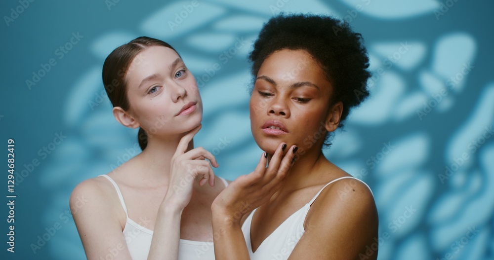 Two young models of different ethnicity are posing looking at the ...