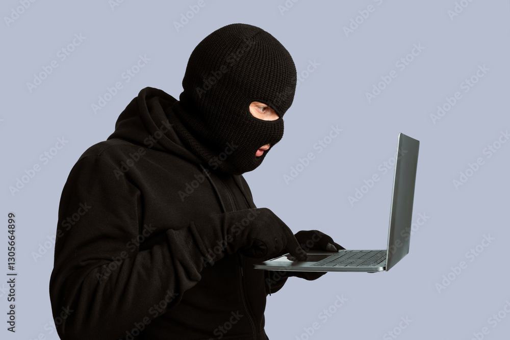 Computer Hacker. Masked criminal wearing black balaclava downloading private information ...