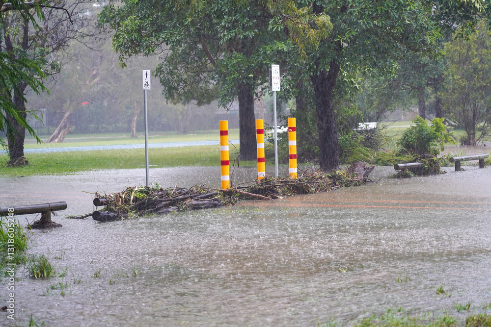 Flooded road and submerged pathway in a park during heavy rain and ...