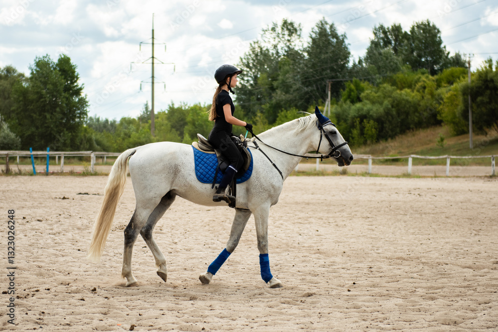 Training process. Young teenage girl jockey wearing helmet riding horse ...
