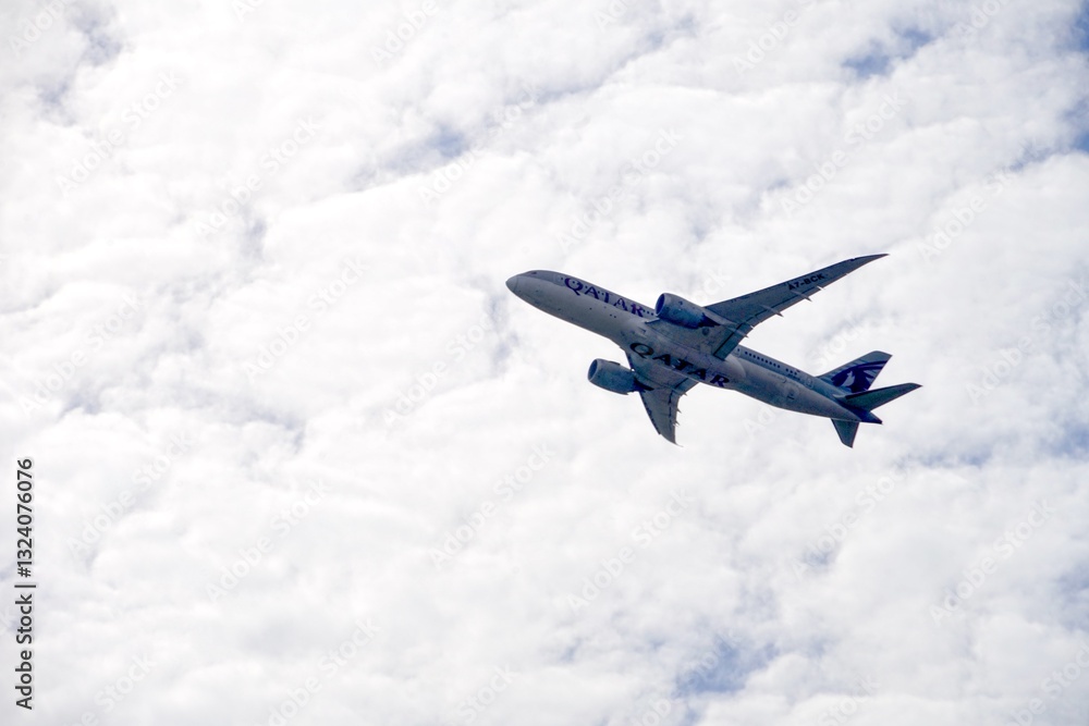 Qatar Airways plane taking off in front of a blue sky with some clouds ...