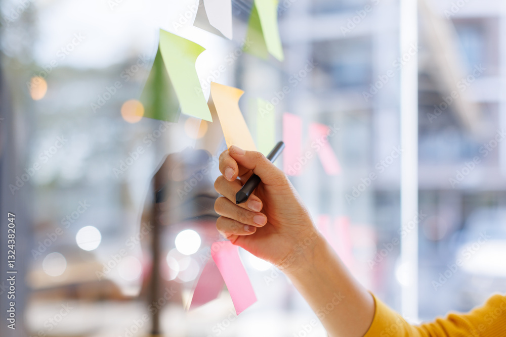 Young asian woman use post it notes to share idea sticky note on glass ...