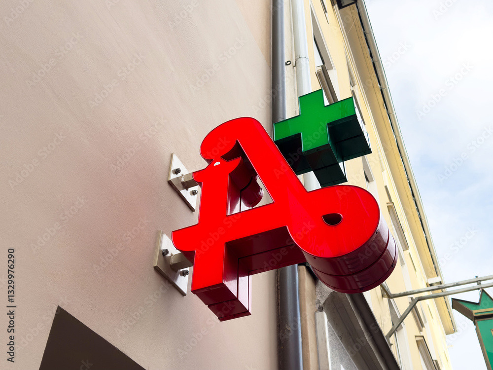 Red pharmacy signage on urban building exterior with green cross symbol ...