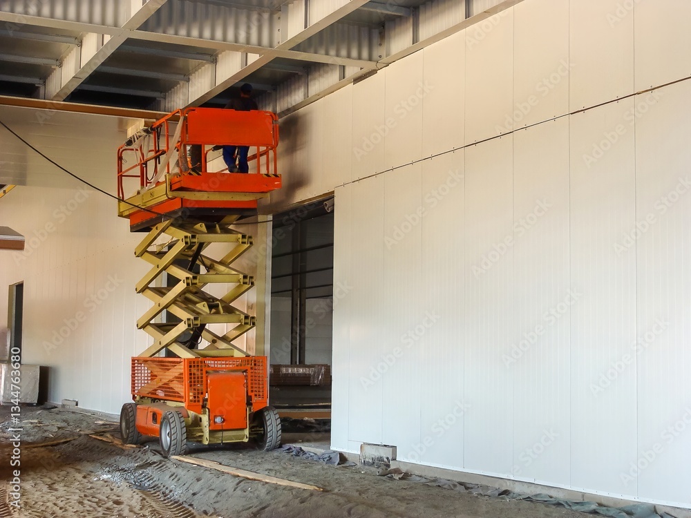 Workers on a scissor lift installing insulated metal panels on the ...