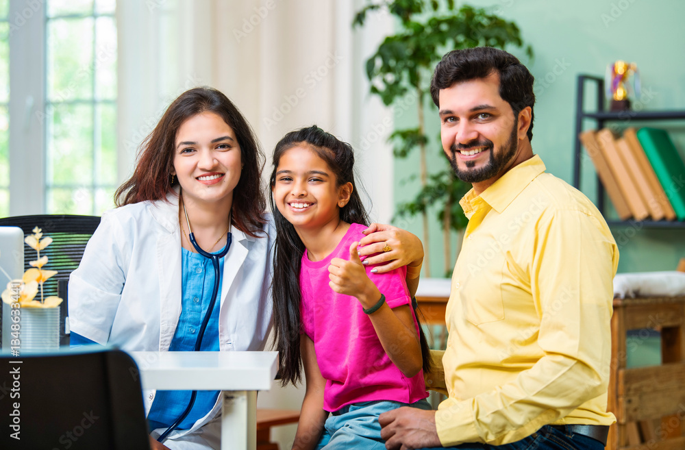 Indian female doctor smiling with a happy child patient, father, posing ...