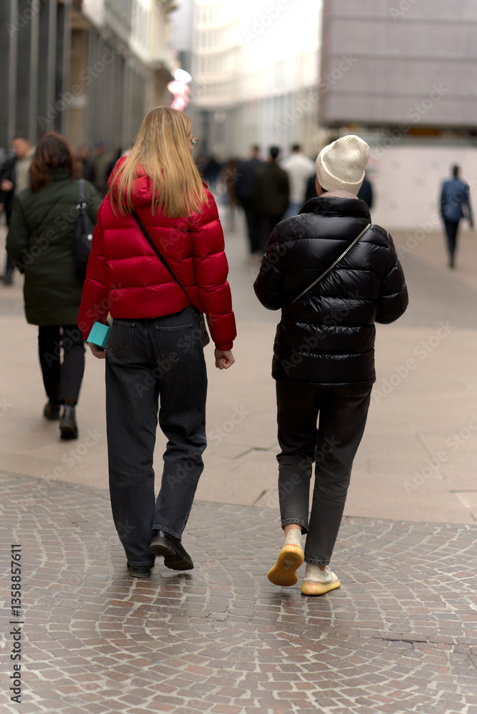 Two women wearing down jackets shopping on a street in Milan. Stock ...