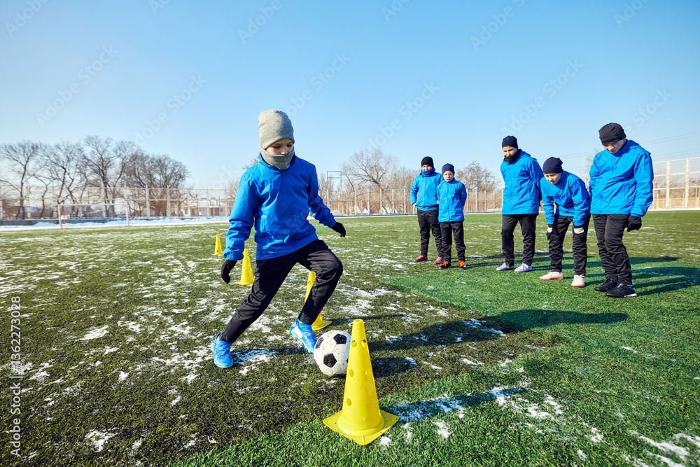 Football player executing dribbling drill while teammates and coach ...