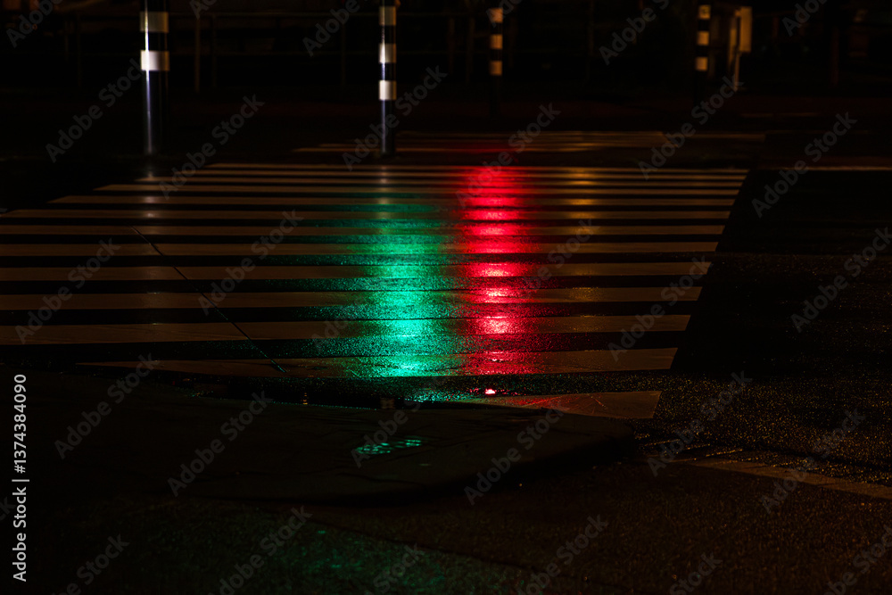 Nighttime city street with a zebra crossing illuminated by reflections ...