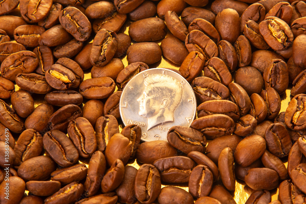 Roasted coffee beans with a U.S. dime for scale on a golden reflective ...