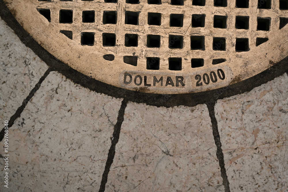 Metal manhole cover on a stone pavement. Round sewer grate with grid ...