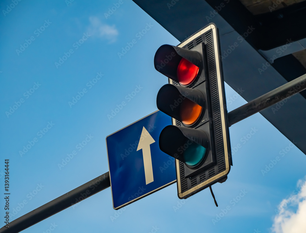 Red traffic light and one-way sign against a clear blue sky. Urban ...