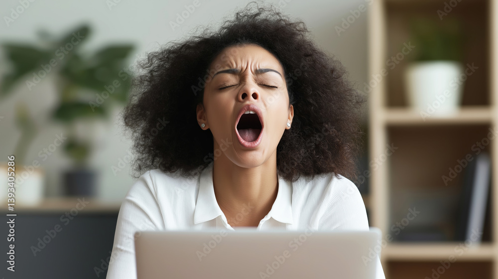 Exhausted female office worker yawning in front of her laptop ...
