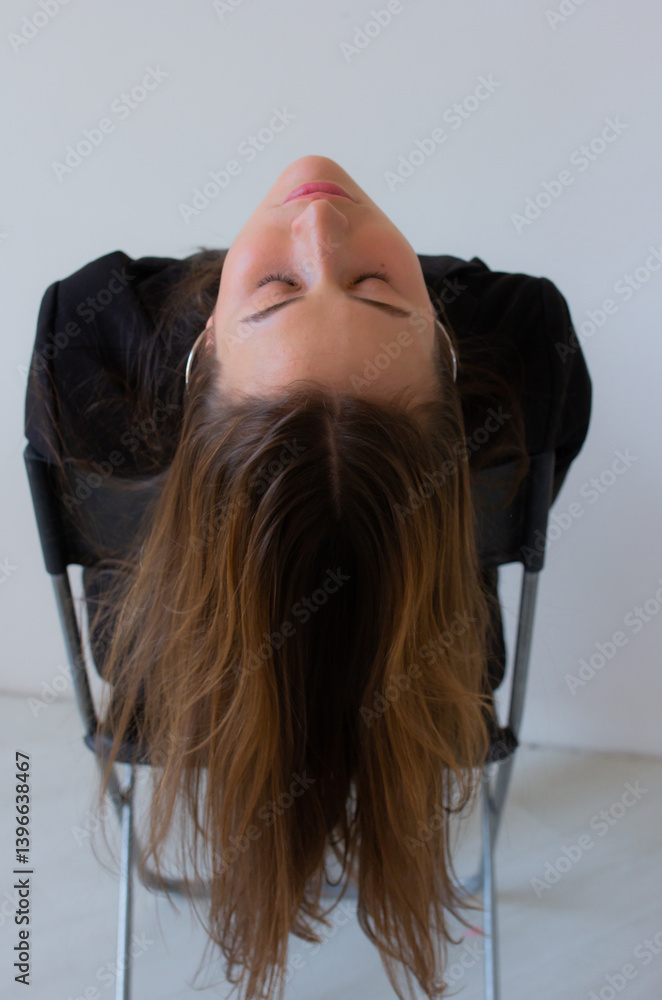 Artistic portrait of a young woman bending backwards over a chair, eyes ...