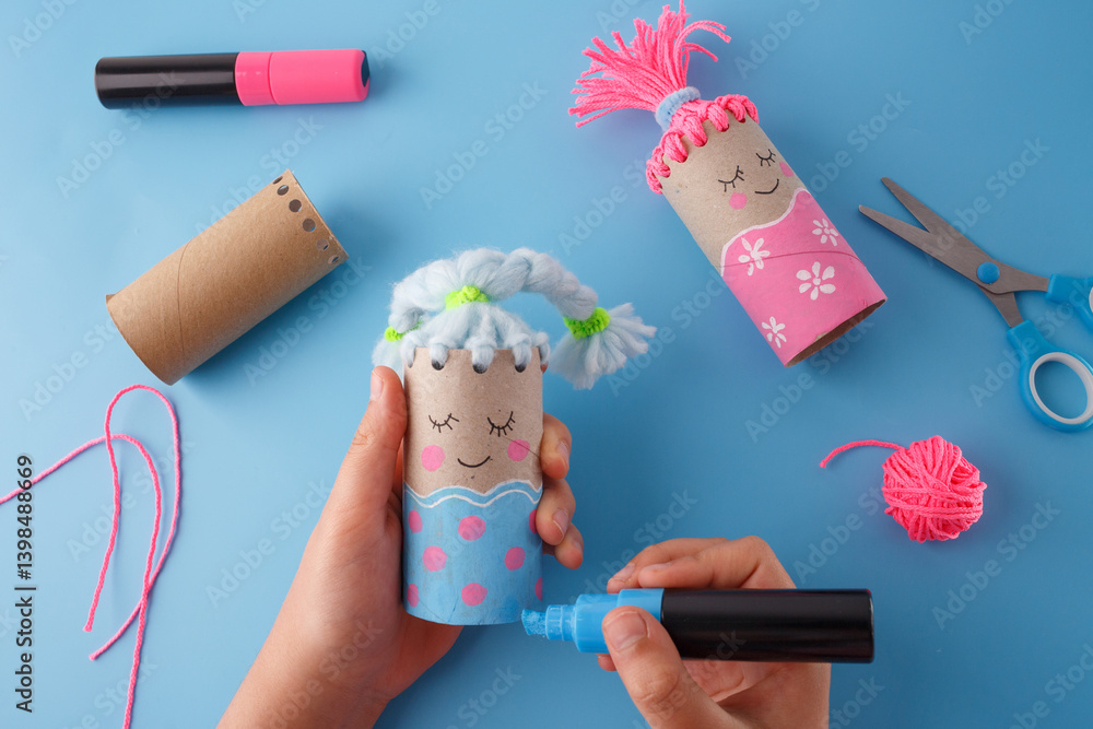 Children making handmade dolls from cardboard tubes using yarn and ...