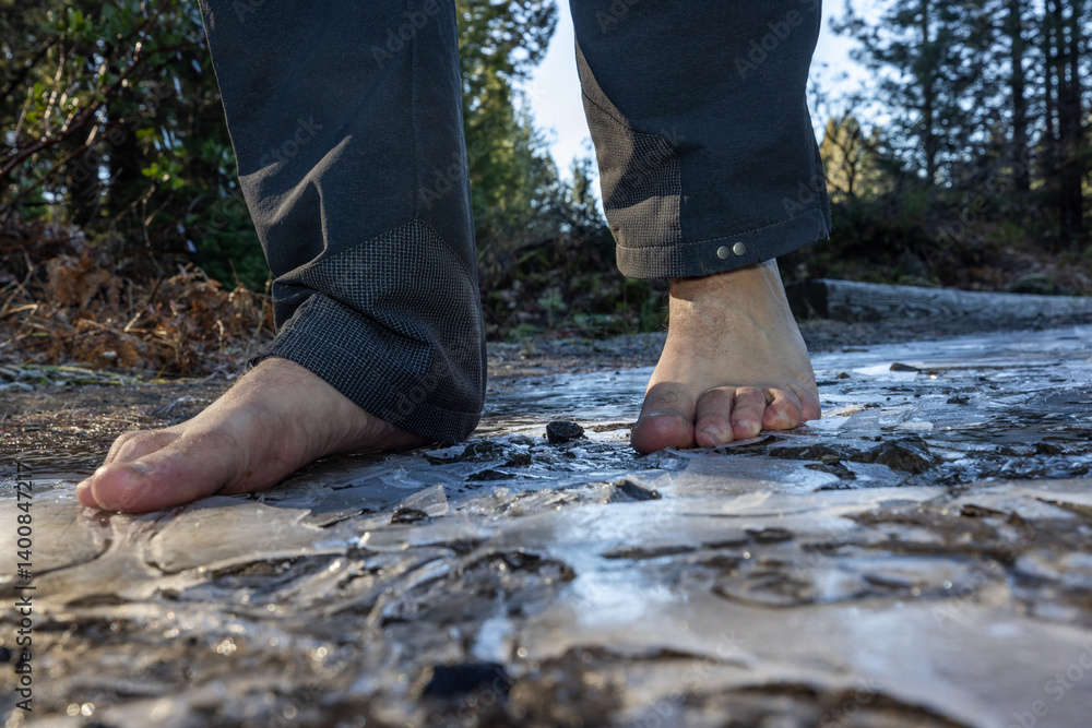 Human feet of an adult male walking barefoot on a frozen puddle as a ...