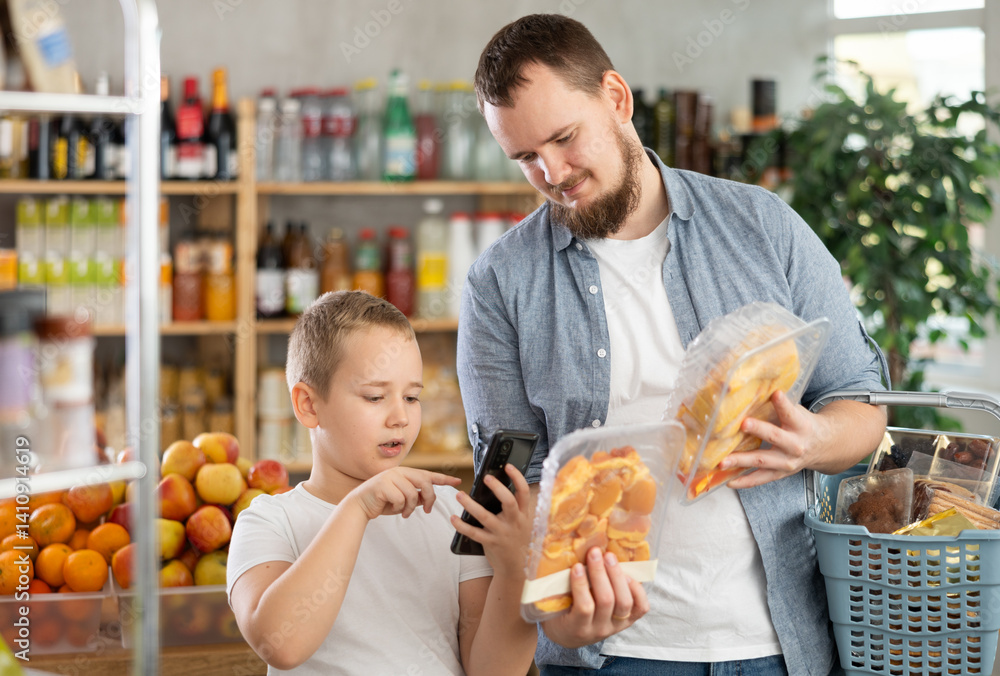 Interested tween boy with friendly young father scanning barcodes on ...