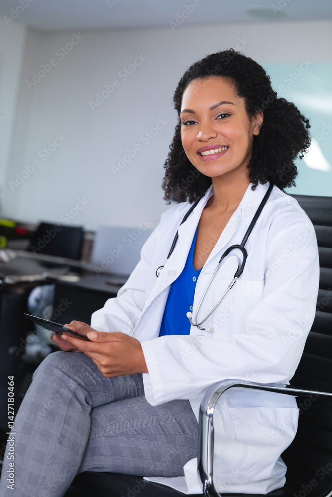 Female doctor sitting on office chair in medical office, holding tablet ...