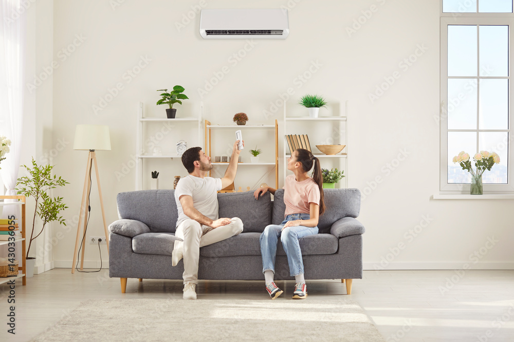 Young couple sitting on sofa in living room at home and setting up a ...