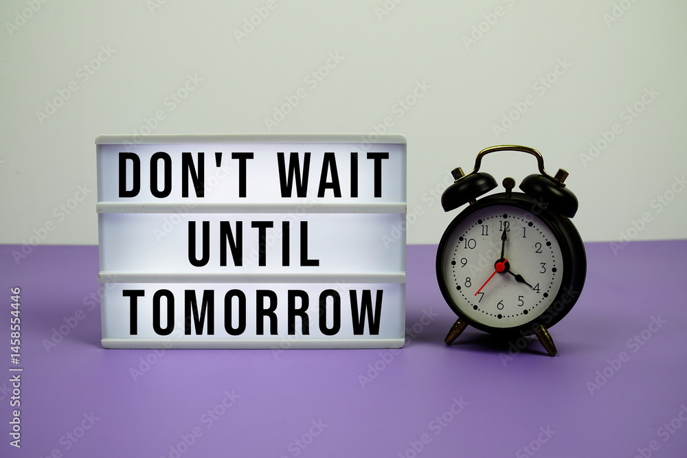 Don't Wait Until Tomorrow text on LED lightbox with alarm clock on ...