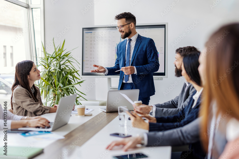 Young leader standing at meeting room with his team around conference ...