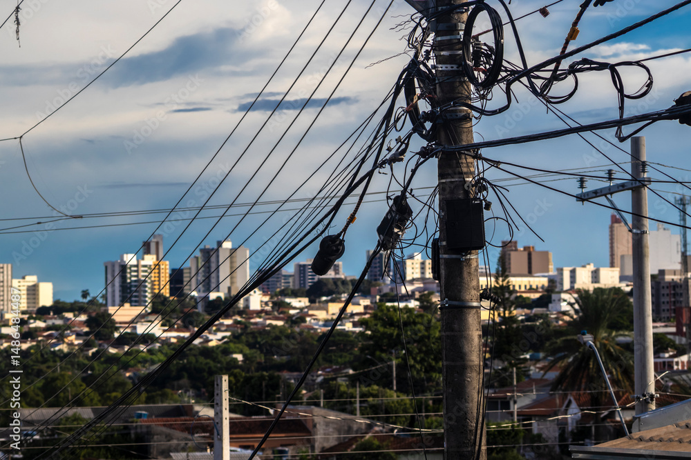 Foto de Stock Tangled wires on a utility pole against a cityscape ...