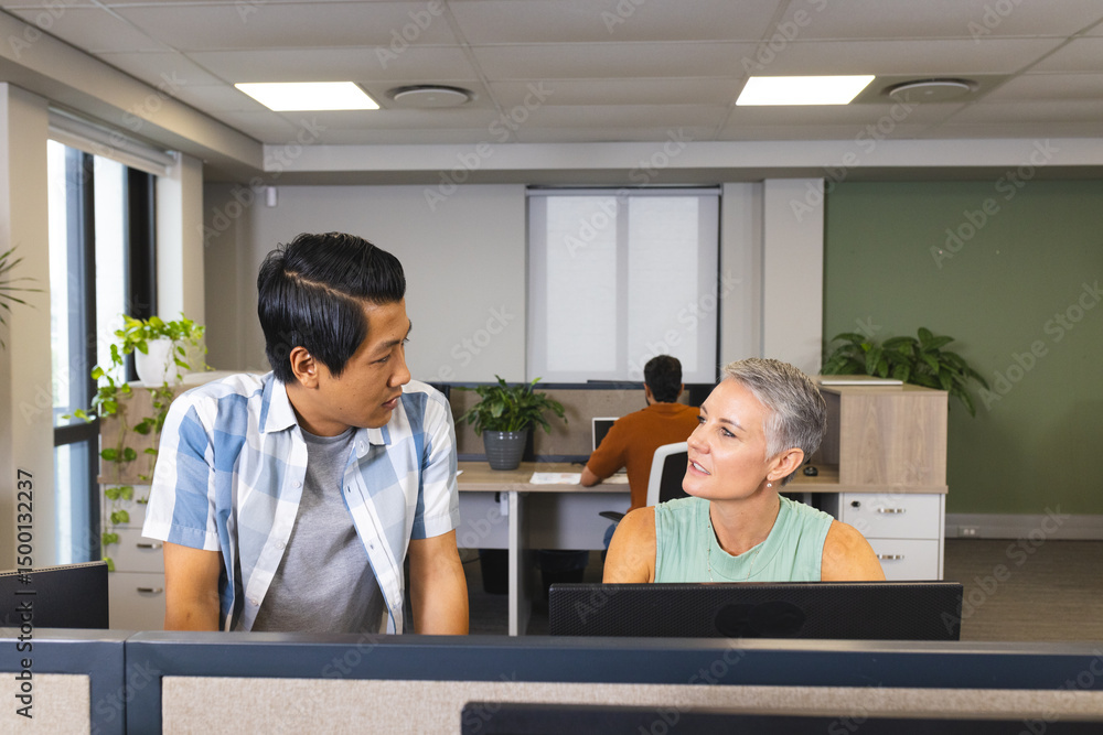 Chatting Diverse coworkers across cubicle partition in office, with ...