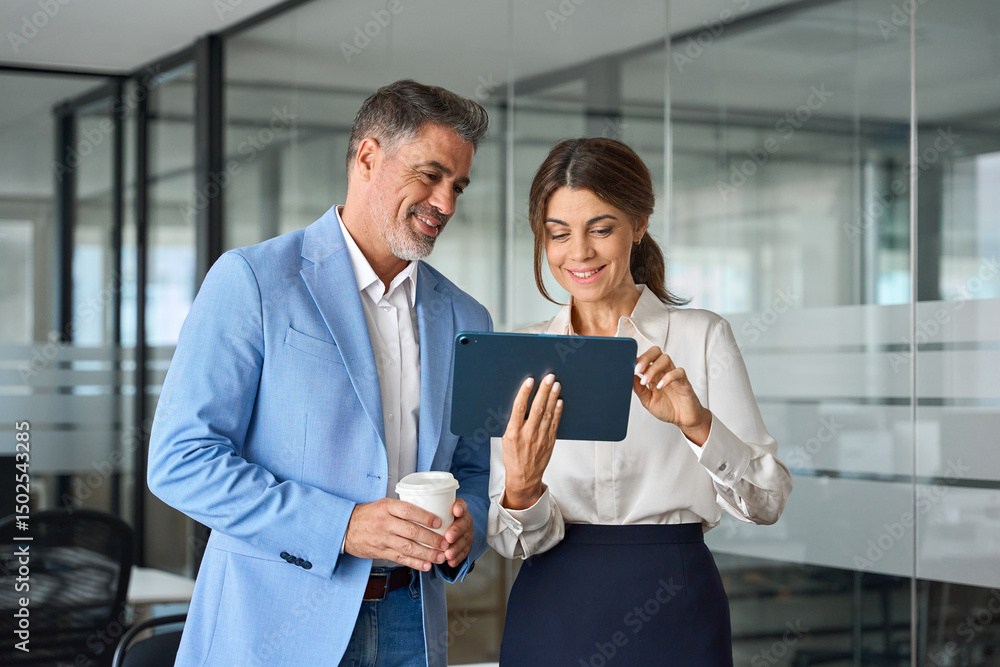 Two busy mature professional executives team business people talking using tablet computer ...